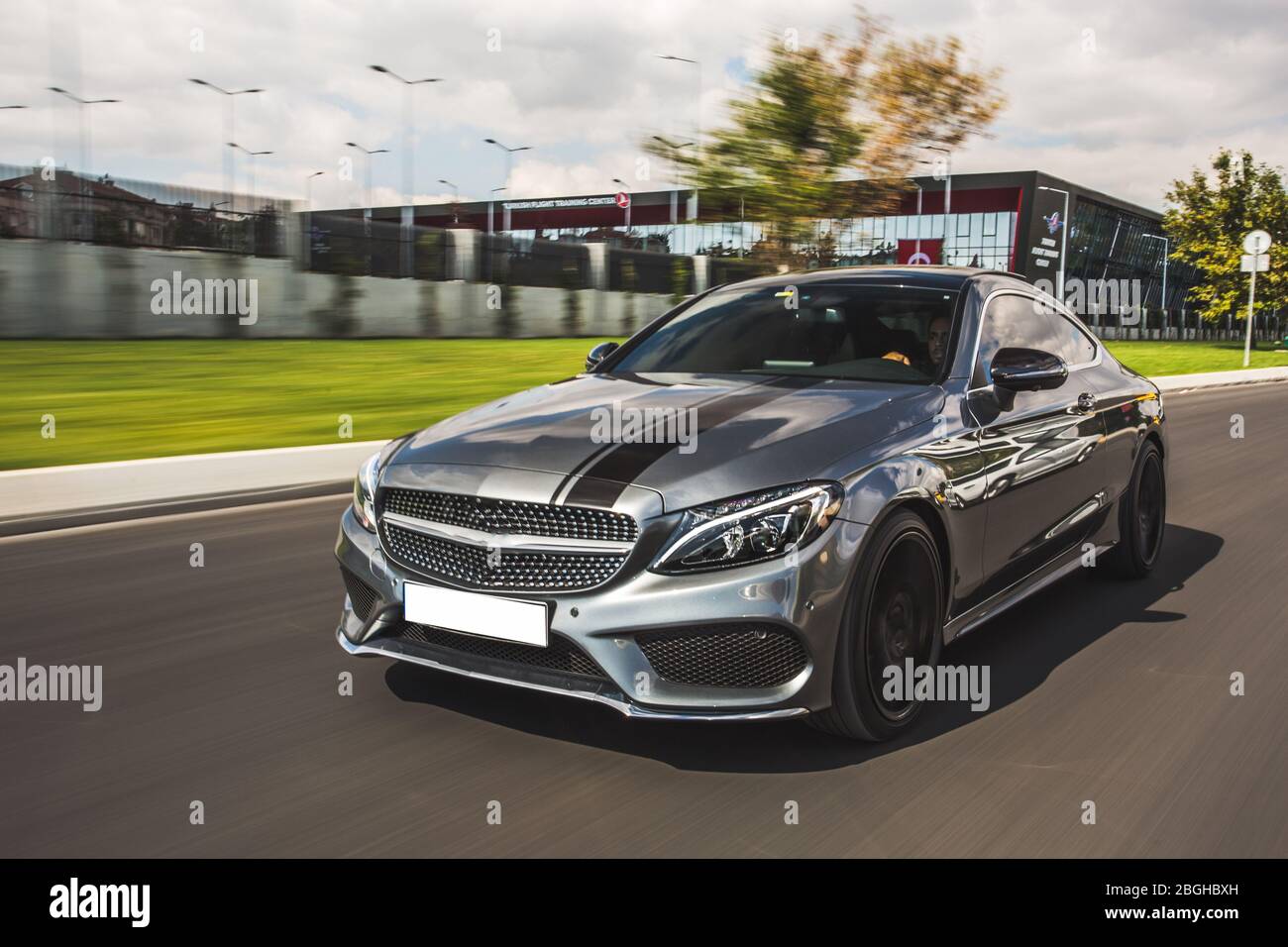 Grey sport car driving across farmhouses Stock Photo - Alamy