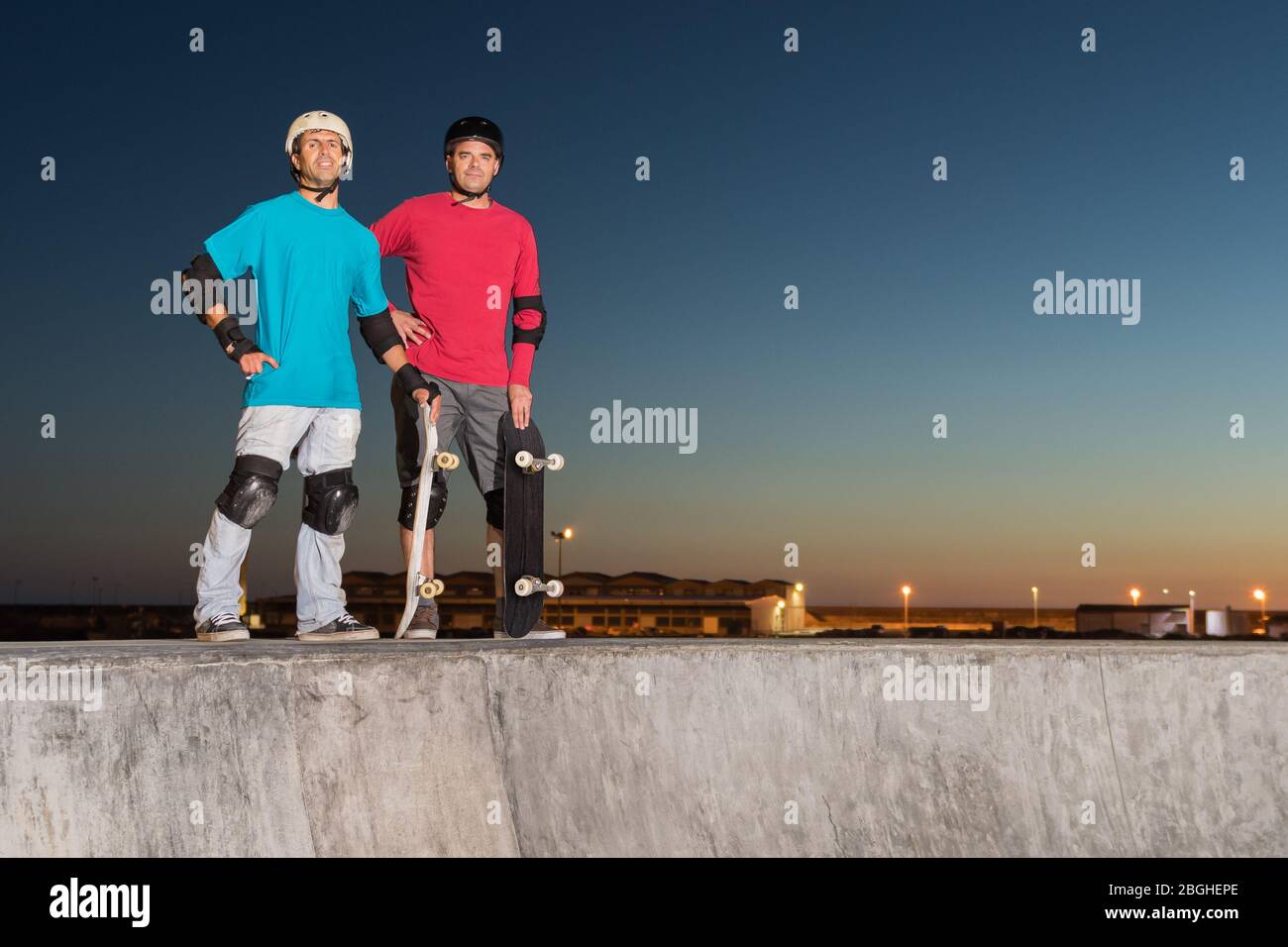 Two skateboarders standing near a concrete pool at skatepark on a ...