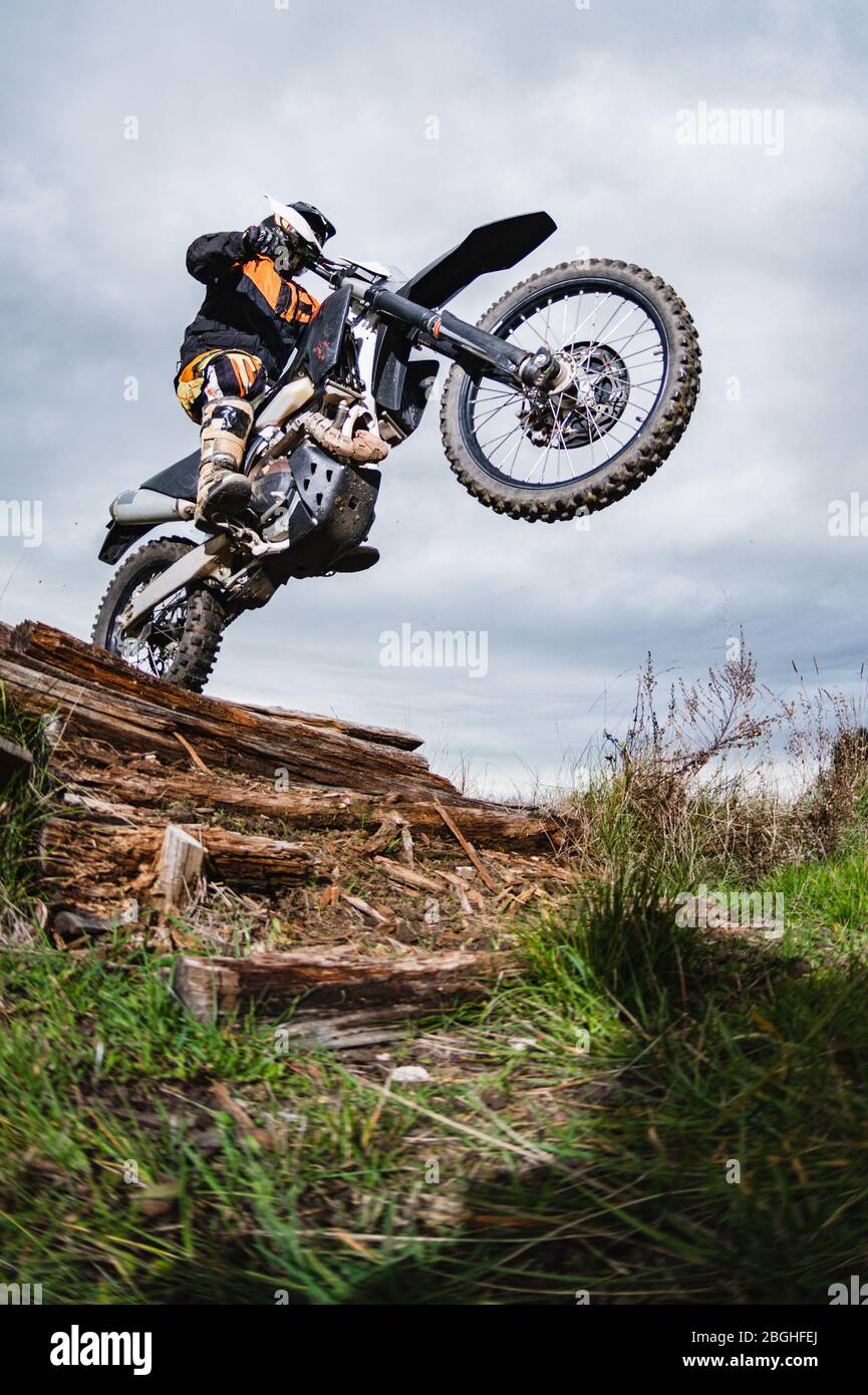 Enduro bike rider in action. Obstacle overcome on mud and grass terrain ...