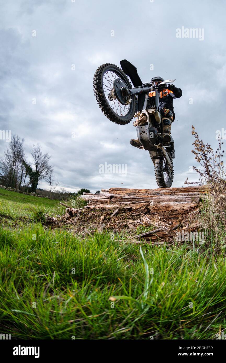 Enduro bike rider in action. Obstacle overcome on mud and grass terrain ...
