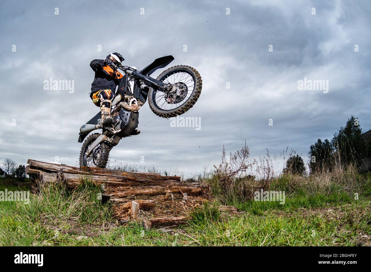 Enduro bike rider in action. Obstacle overcome on mud and grass terrain ...