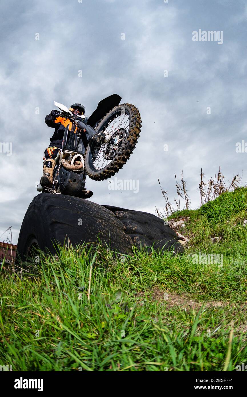 Enduro bike rider in action. Obstacle overcome on mud and grass terrain ...