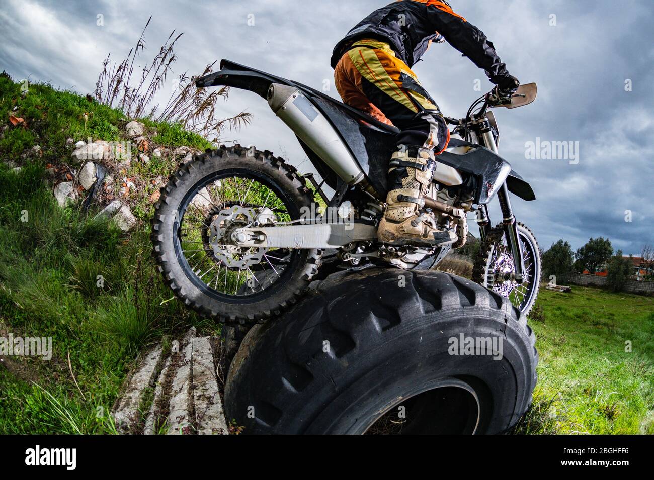 Enduro bike rider in action. Obstacle overcome on mud and grass terrain ...
