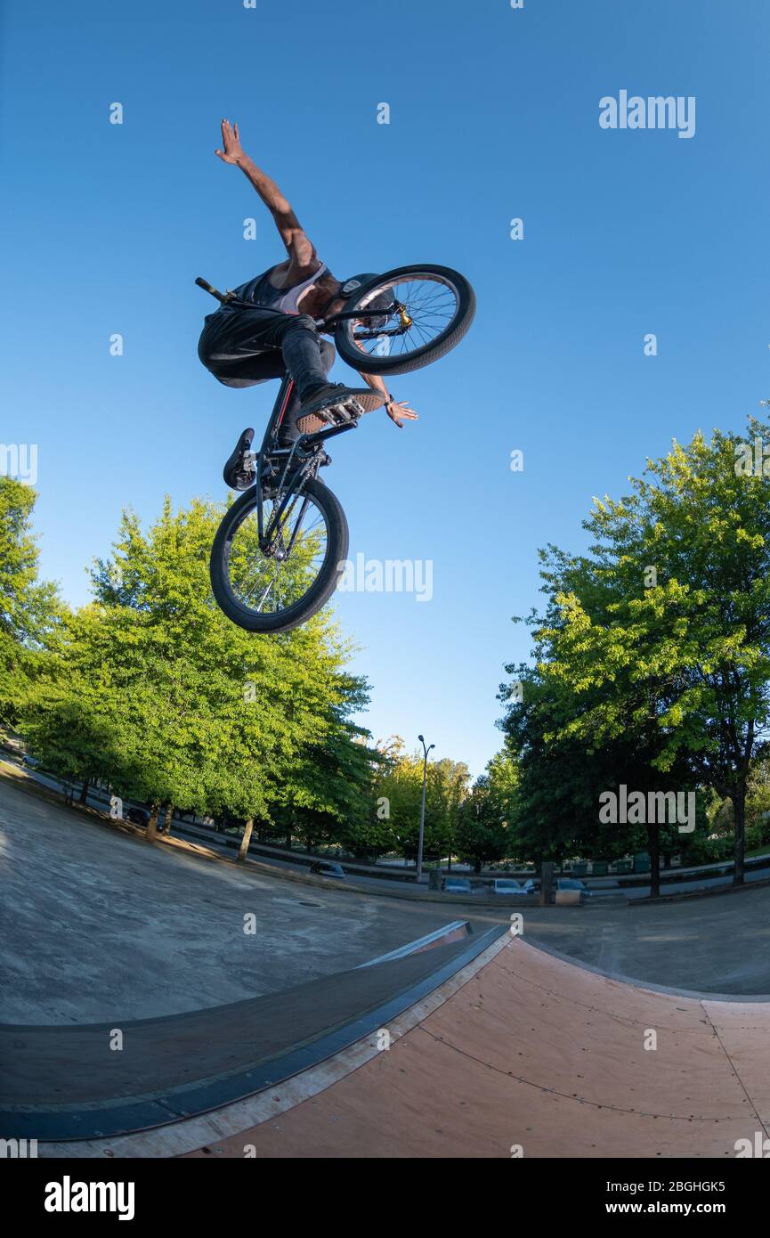 Biker jump high from jump box ramp performing hands off the handlebars ...