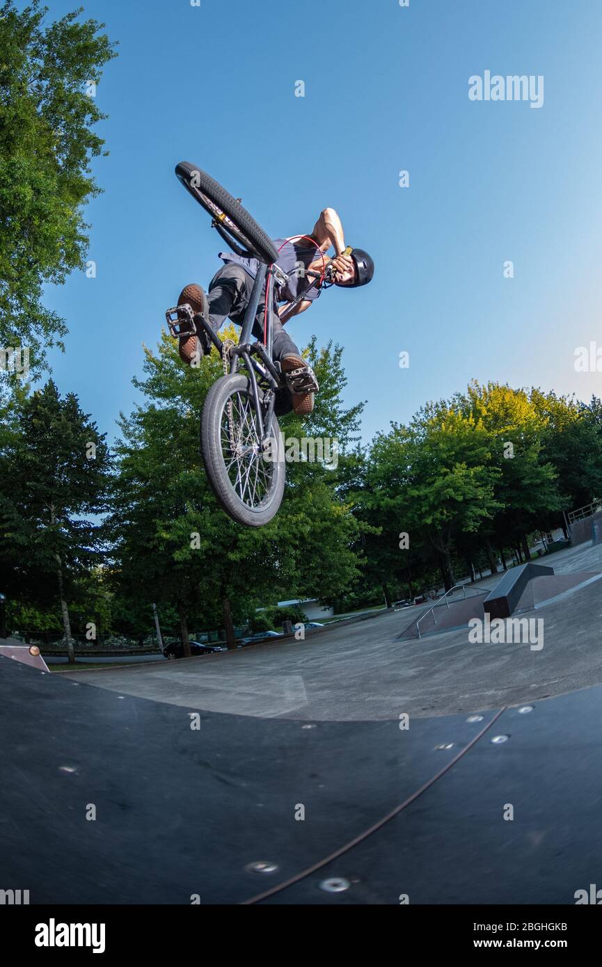 Biker jump high from jump box ramp performing cross bar trick Stock ...