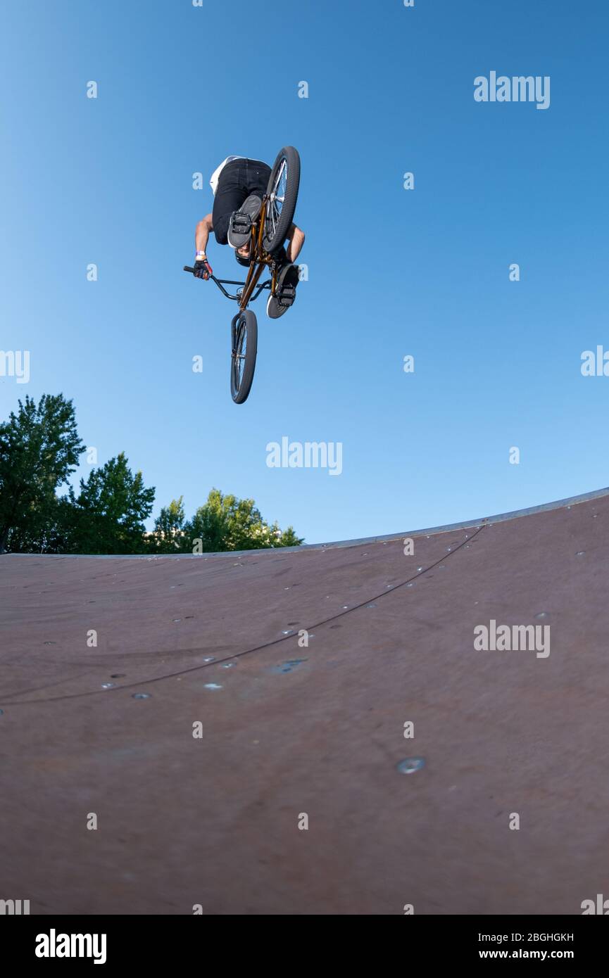 Biker jump high from jump box ramp performing 360 trick Stock Photo - Alamy