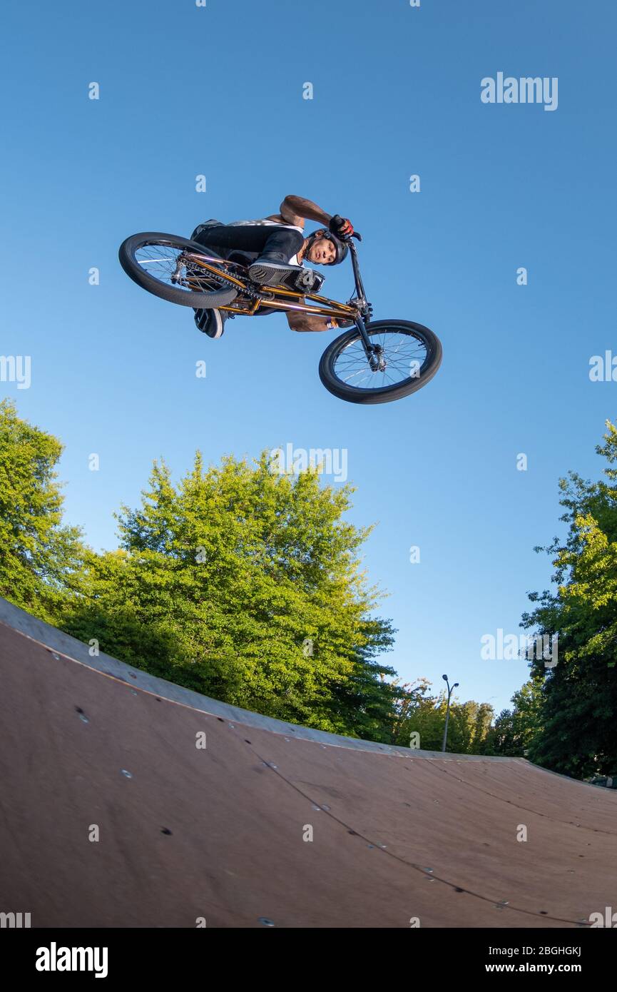 Biker jump high from jump box ramp performing 360 trick Stock Photo - Alamy
