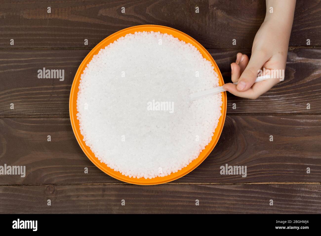 A child eats plastic pellets from a plate .Concept of environmental ...