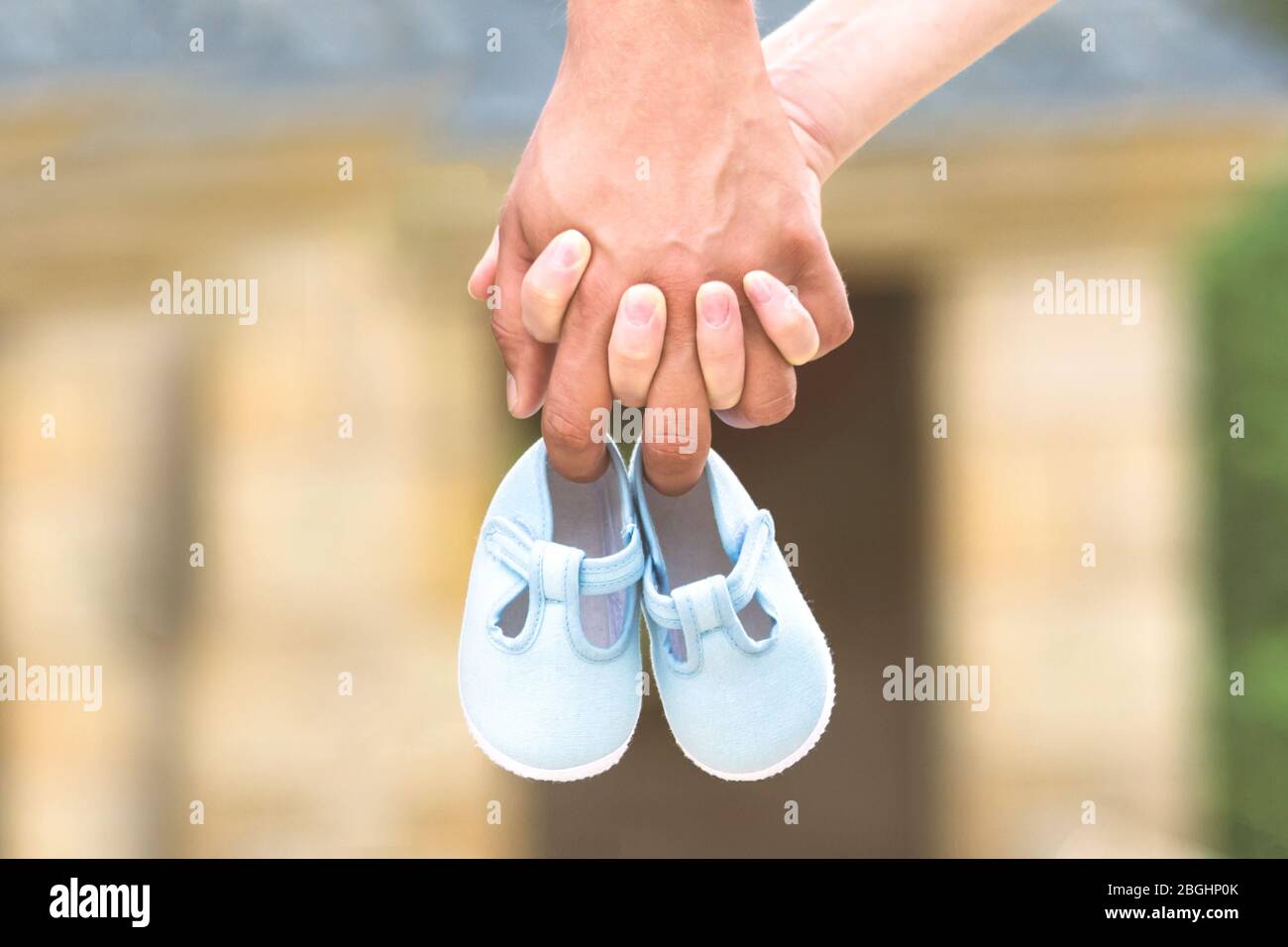 Men's and women's hands hold blue children's shoes. Waiting of baby ...