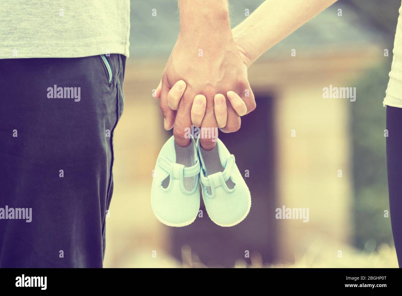 Men's and women's hands hold blue children's shoes. Waiting of baby ...
