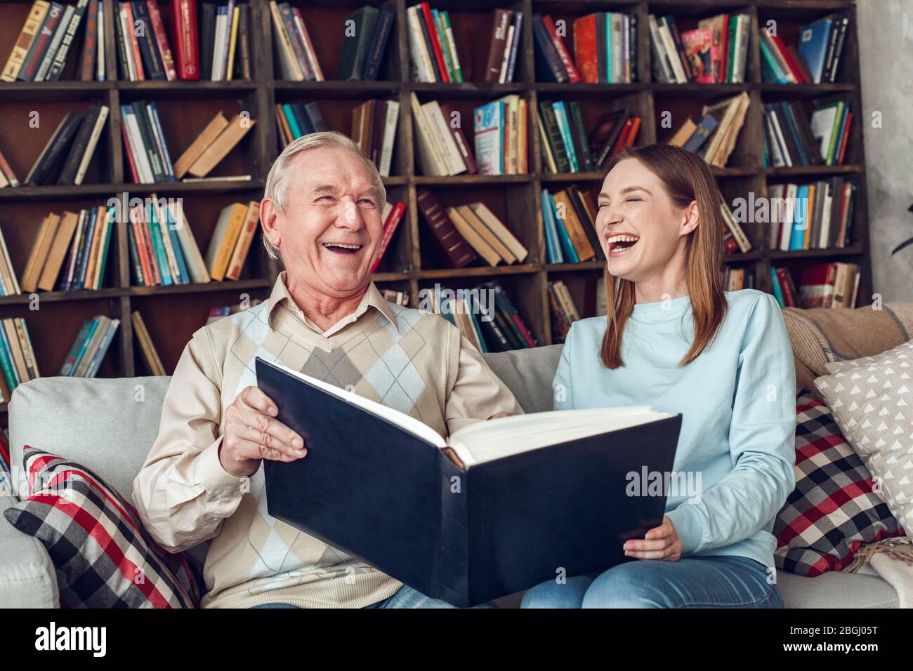 Father and daughter at home library sitting holding album laughing ...
