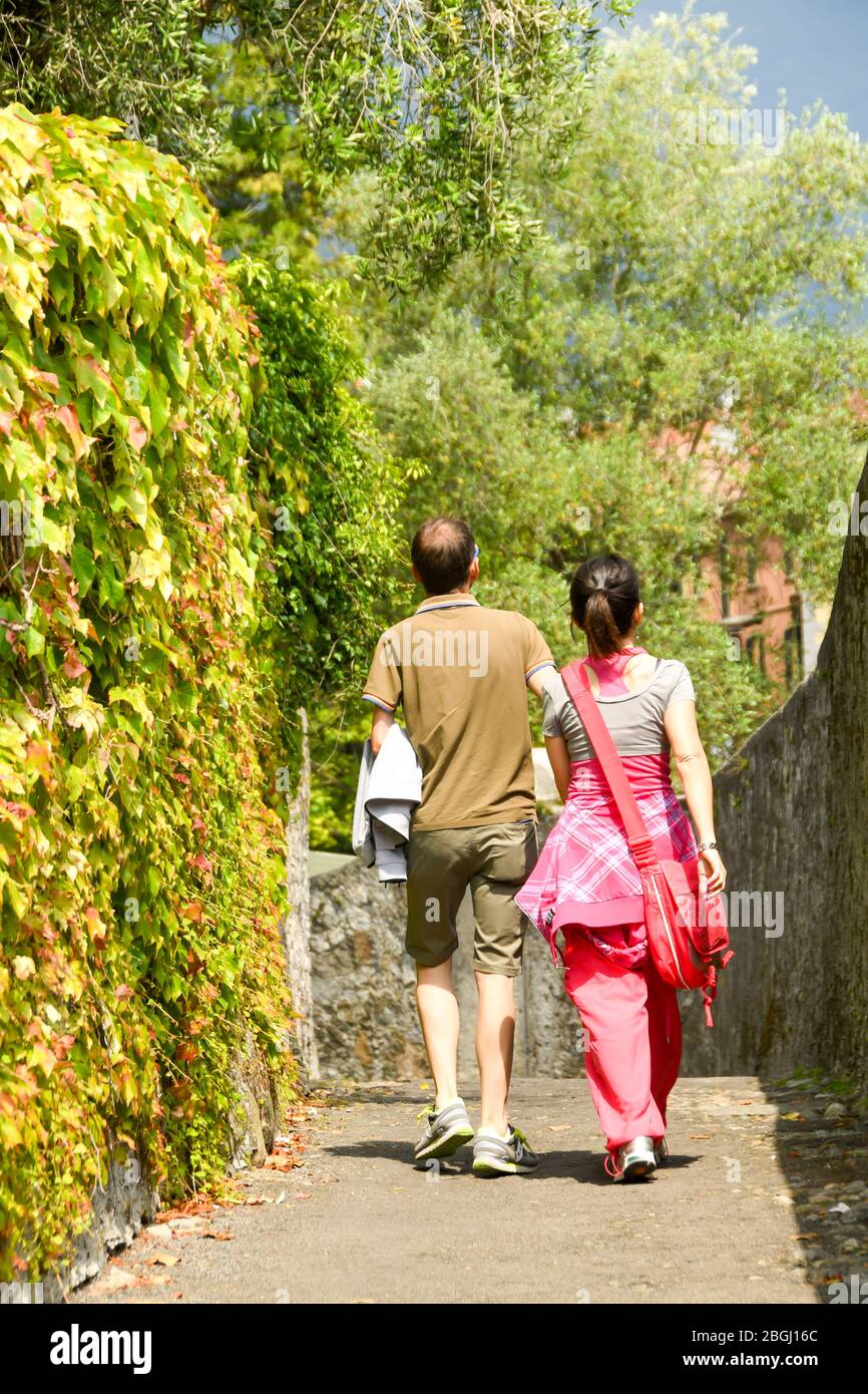 BELLAGIO, LAKE COMO, ITALY - JUNE 2019: Man and woman walking in one of ...