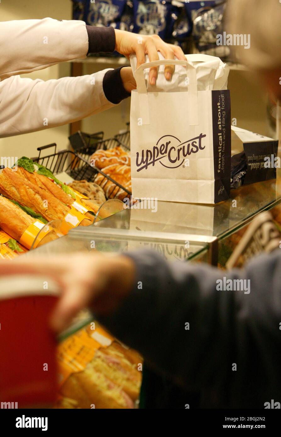 An Upper Crust employee bagging up a customer's purchase at Euston ...