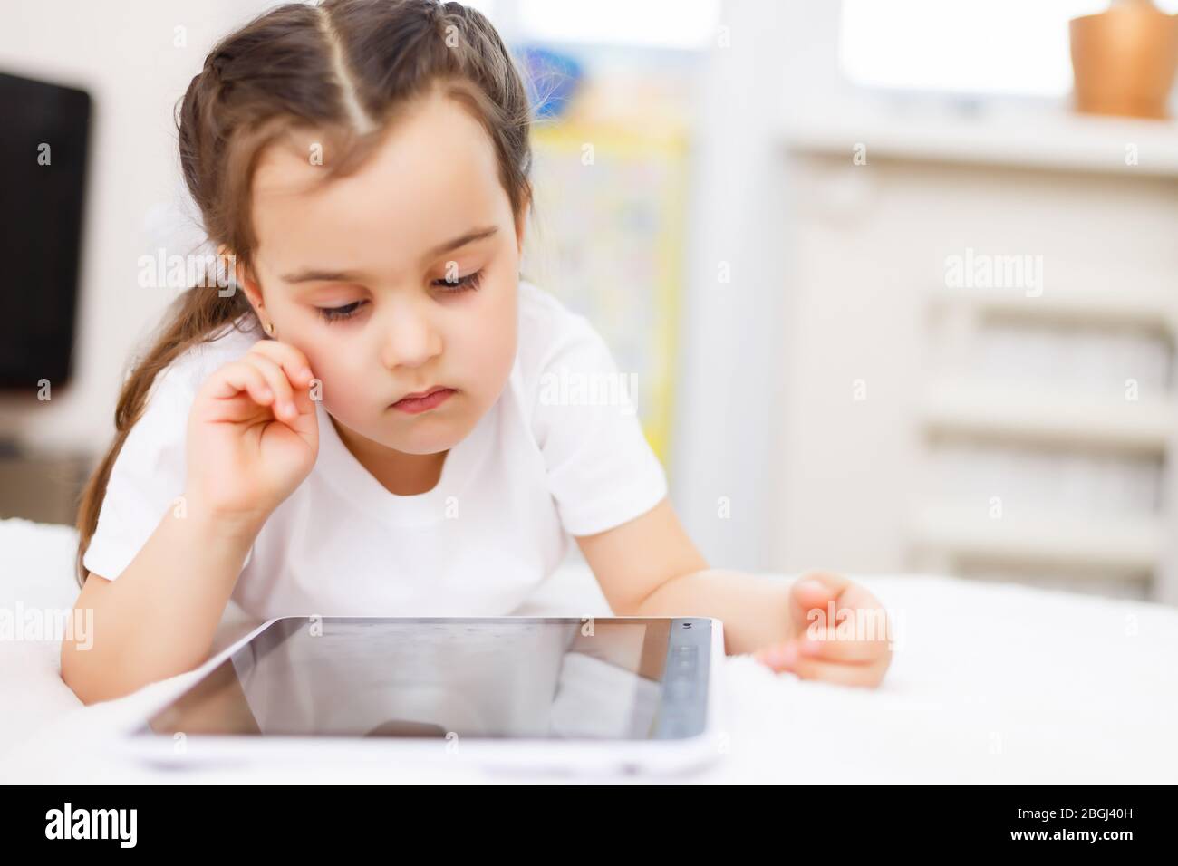 Curious little child girl having fun using digital tablet alone sitting ...