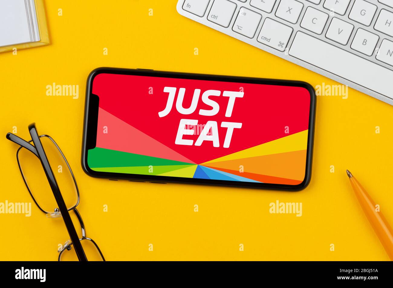A smartphone showing the Just Eat logo rests on a yellow background ...