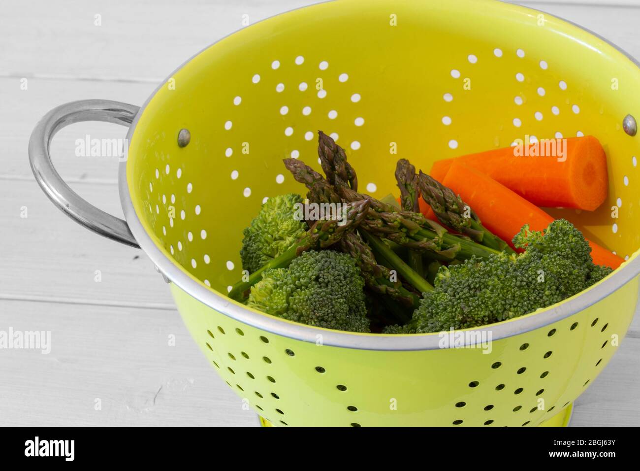 Washed asparagus, broccoli and carrot vegetables in a bright green ...