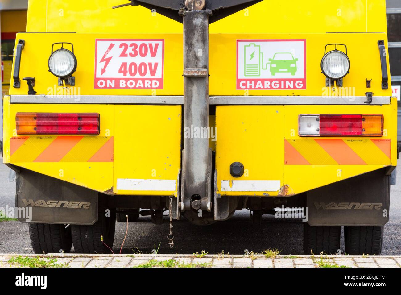 Yellow tow truck rear view with 230V 400V on board sign and electric ...