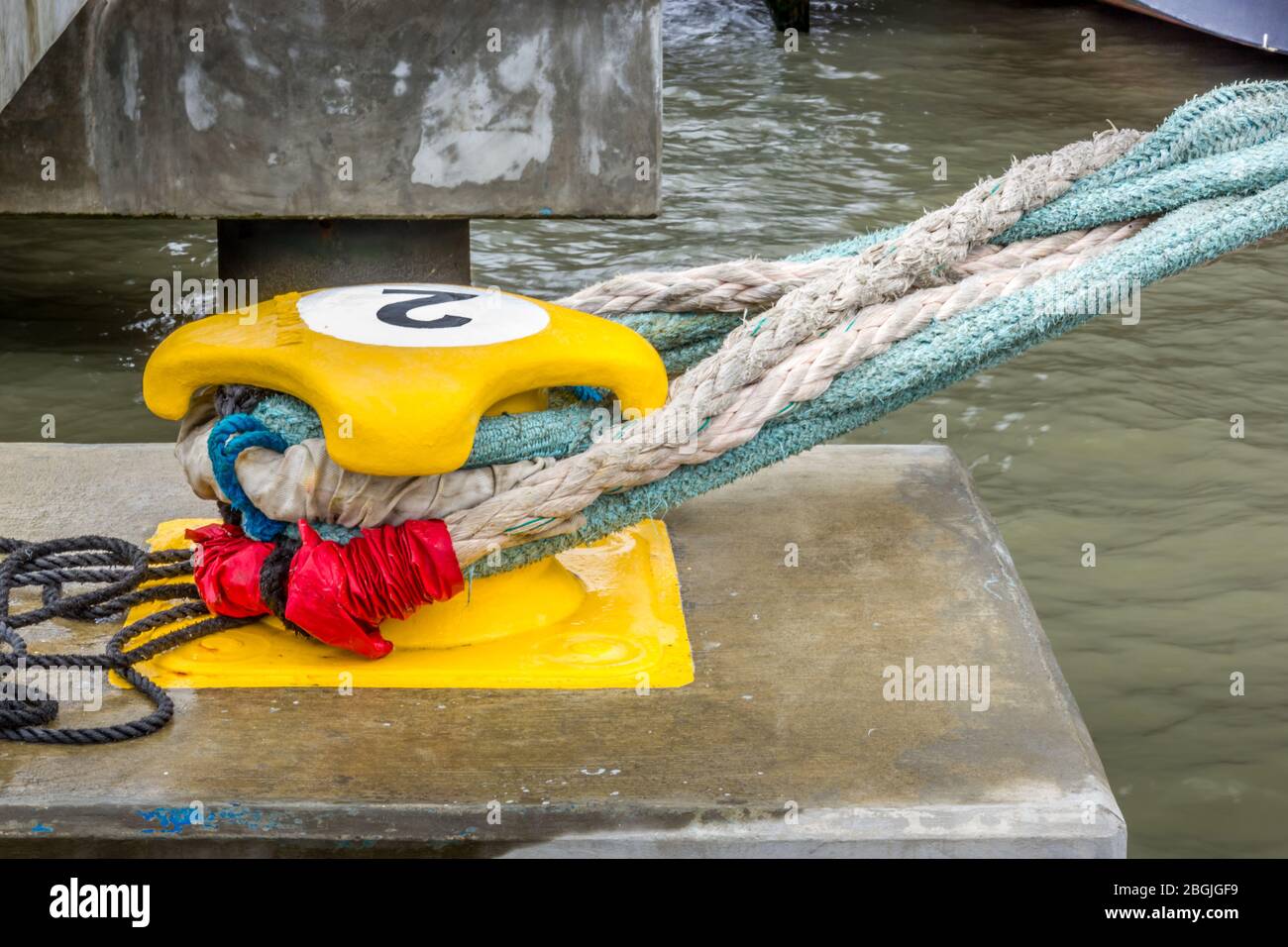A mooring bollard entwined with mooring ropes. Moored ships at the port ...