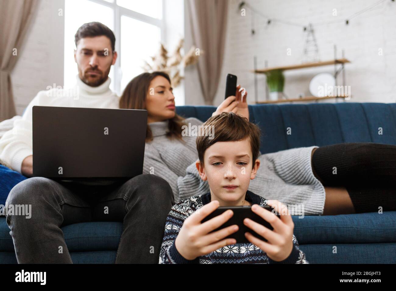 Mother, father and son using laptop and mobile phones at home. Family ...