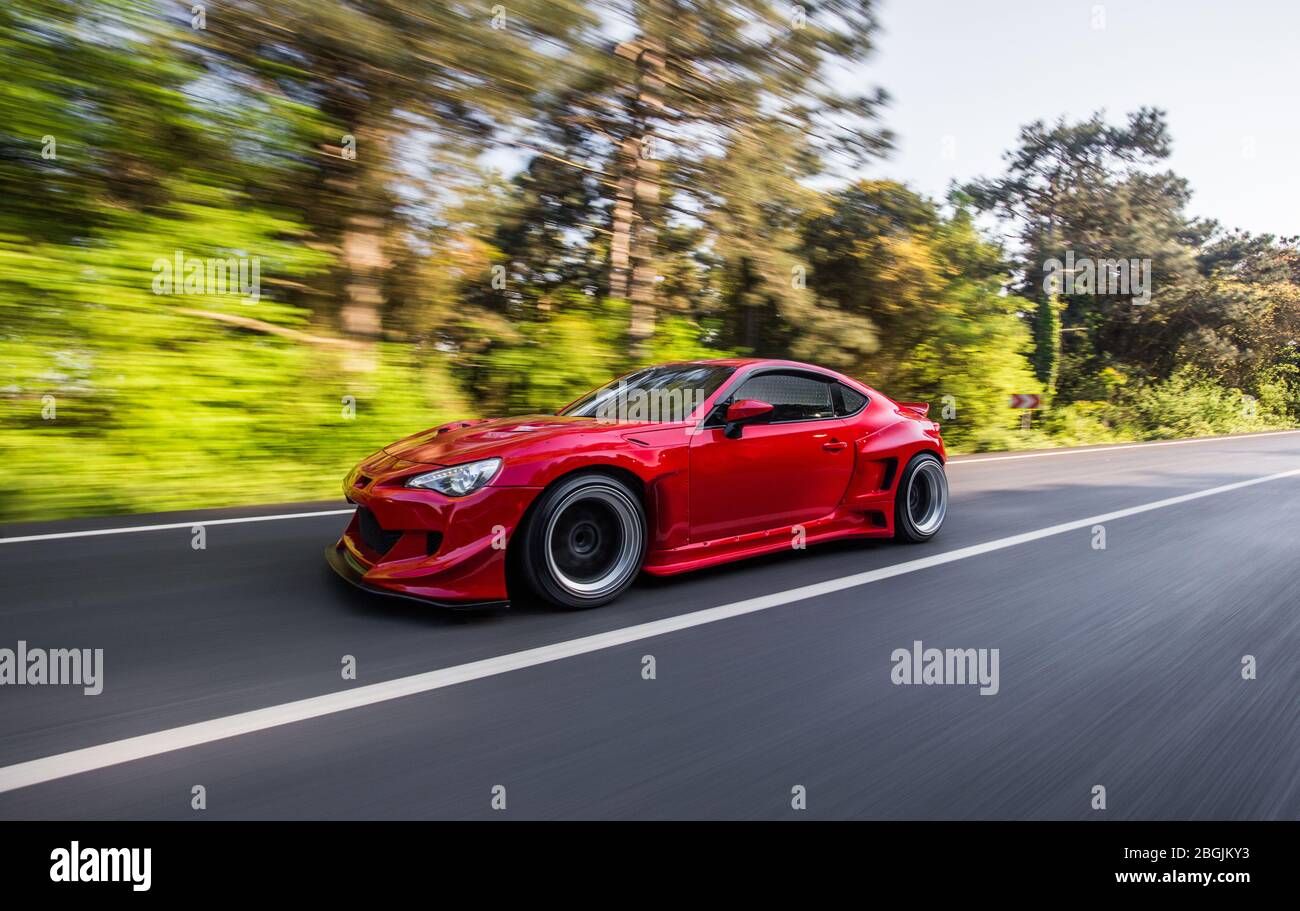 Superpower red racing car on the landscape drive through rain forests ...