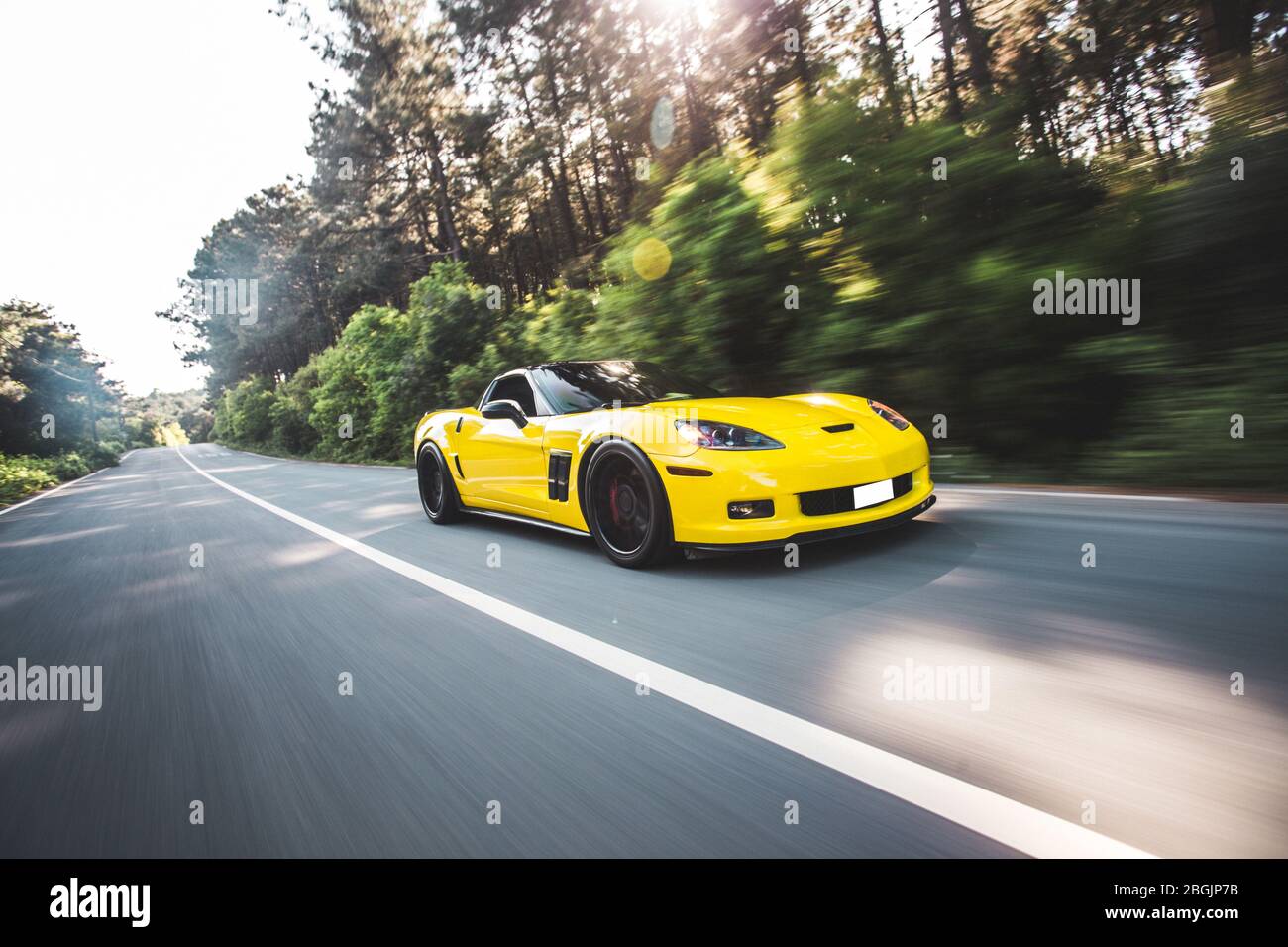 Yellow supercar speed motion through forest, front view Stock Photo - Alamy