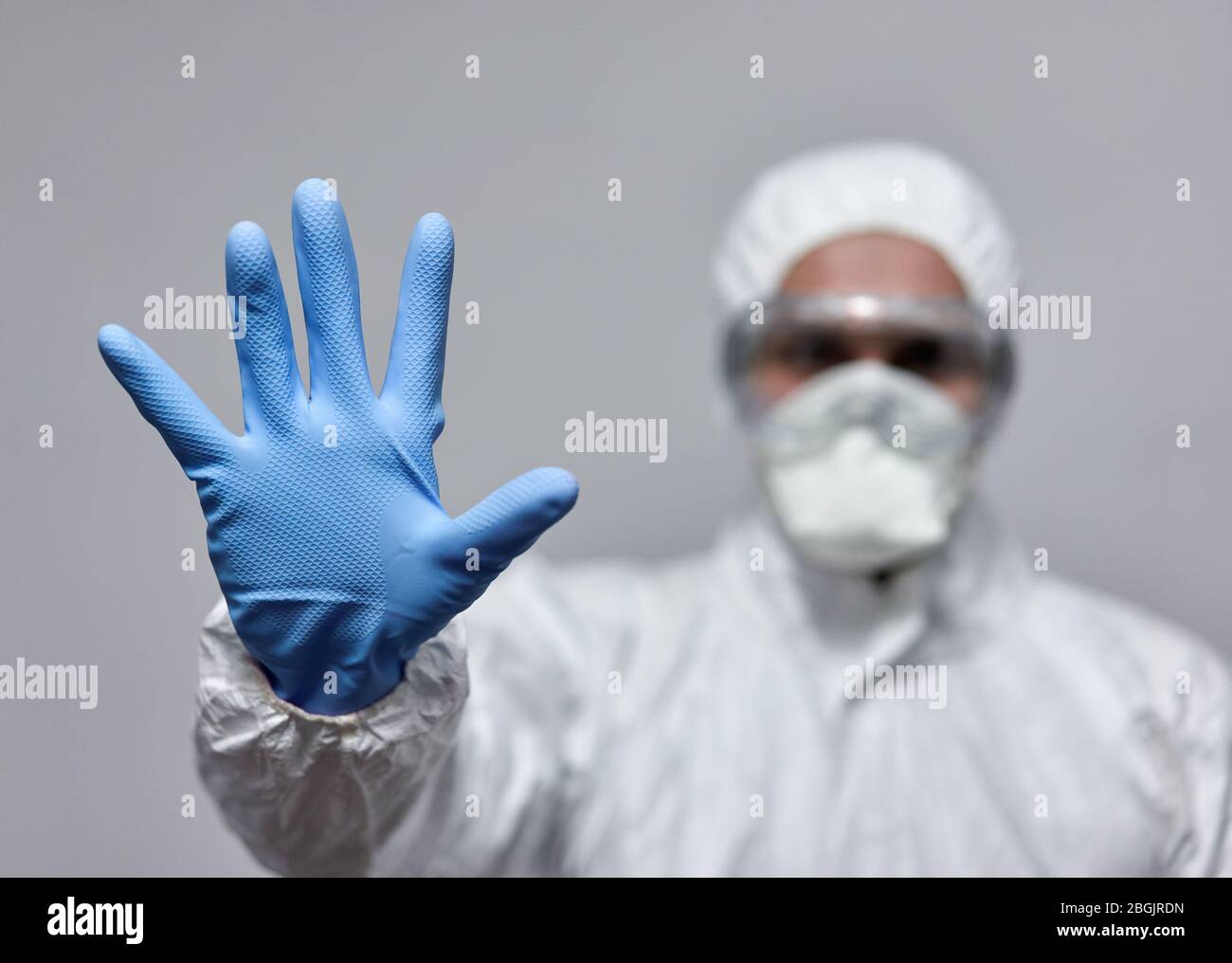Man in overall protection suit against coronavirus making stop sign ...