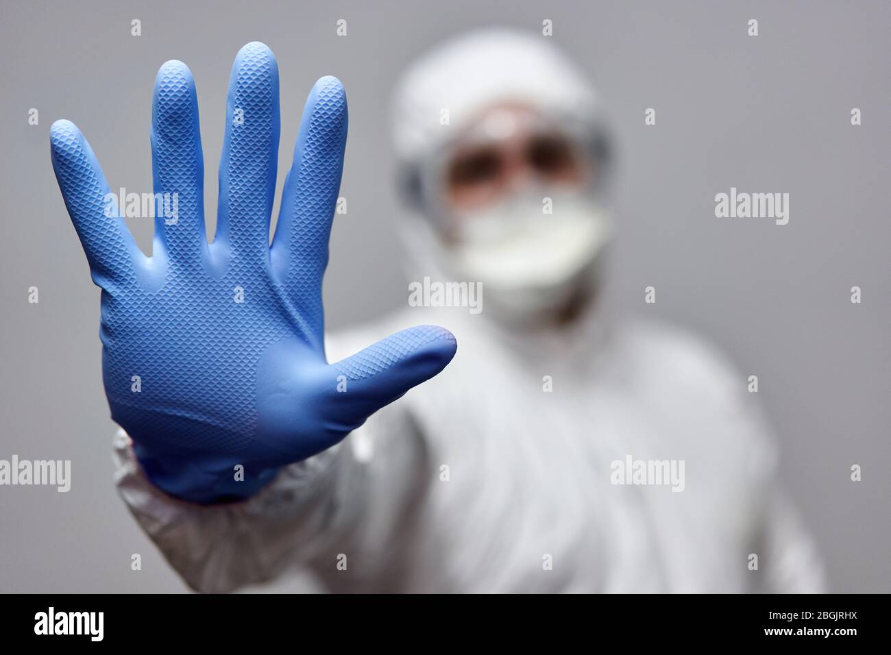 Man in overall protection suit against coronavirus making stop sign ...