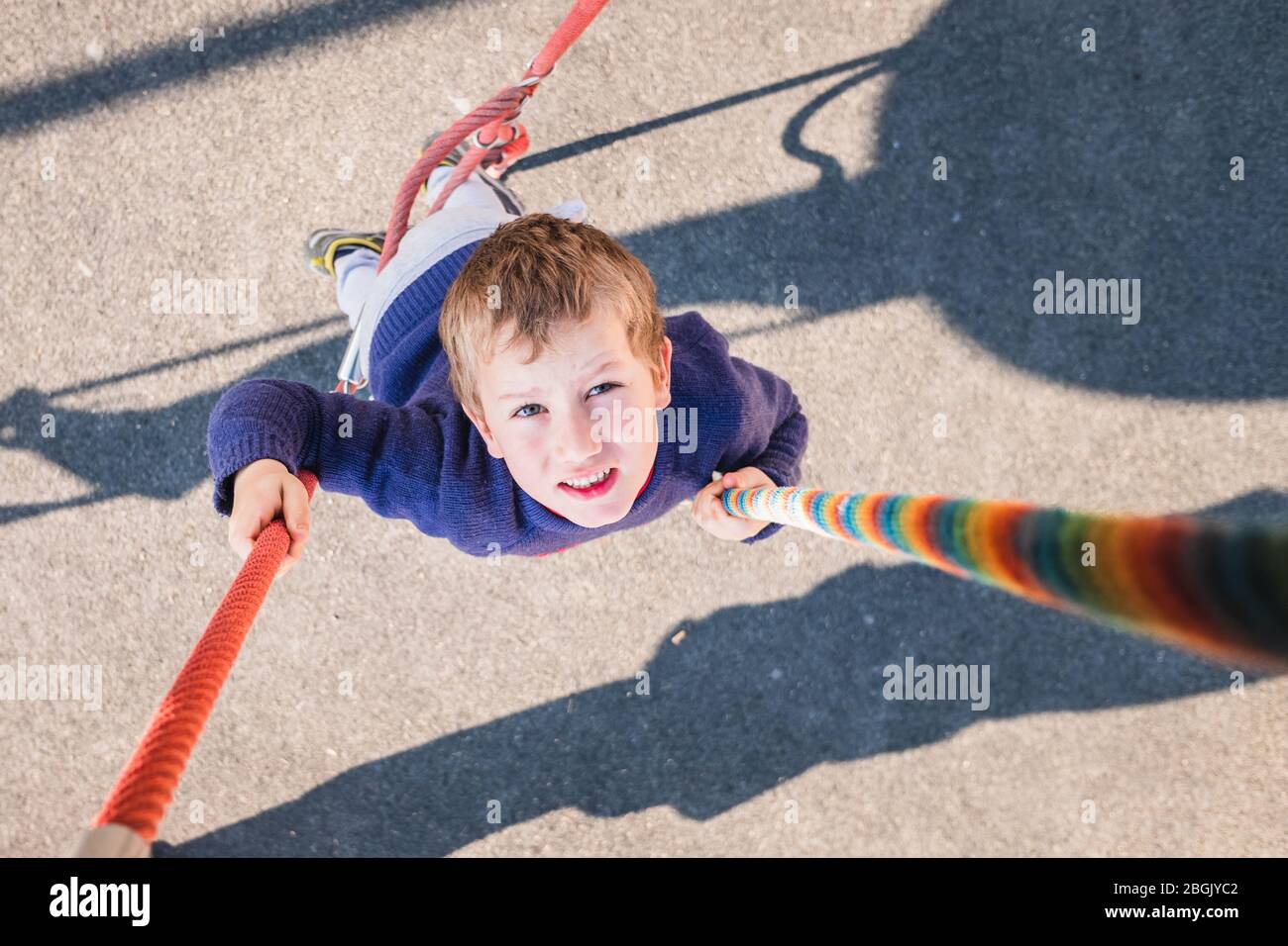 Young boy clinging to a rope in an adventure playground Stock Photo - Alamy