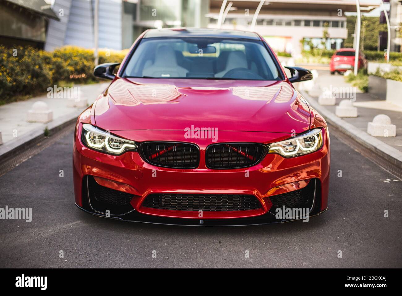Red model sedan in the business quarter, front view Stock Photo - Alamy