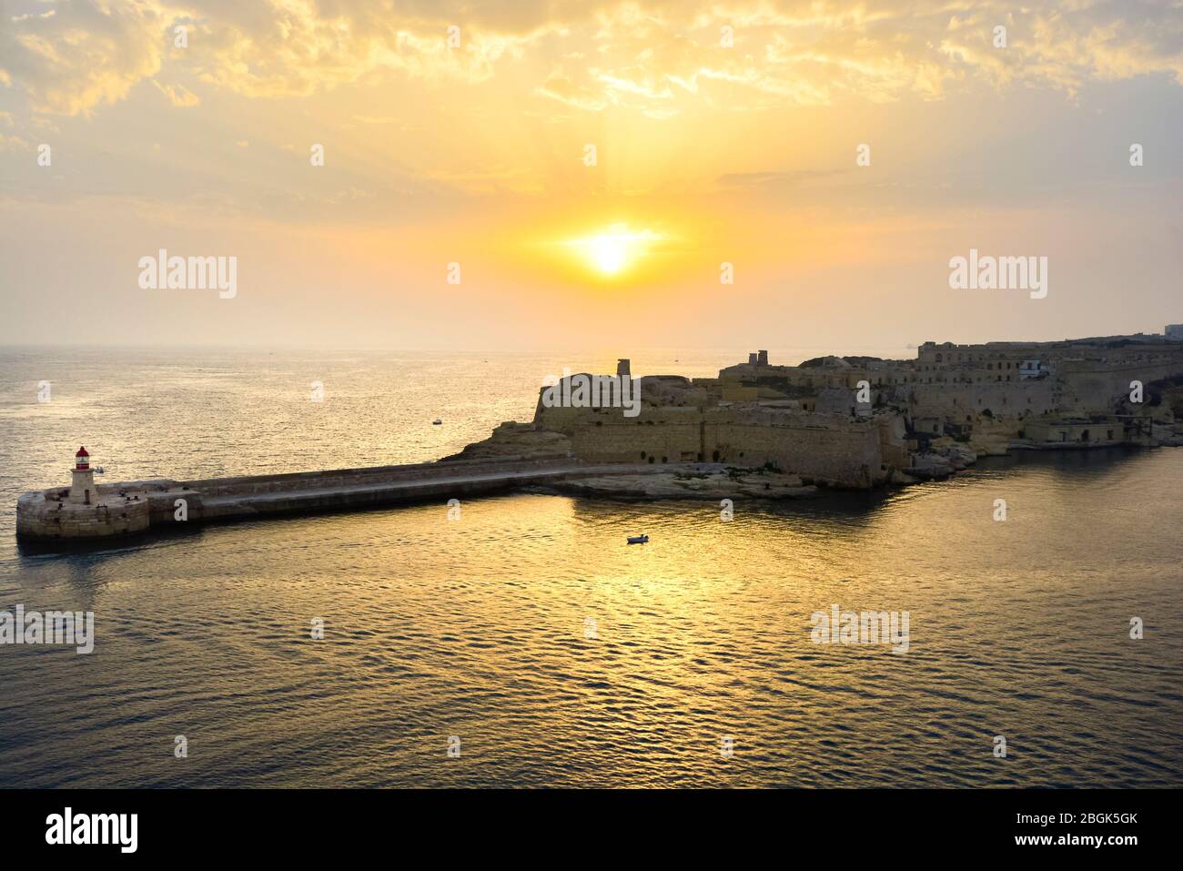 Sunset view of the Ricasoli Point lighthouse at the Valletta port on the Mediterranean island of ...