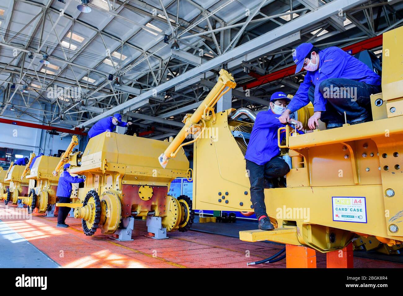 Workers are busy at assembling construction machines along automatic ...