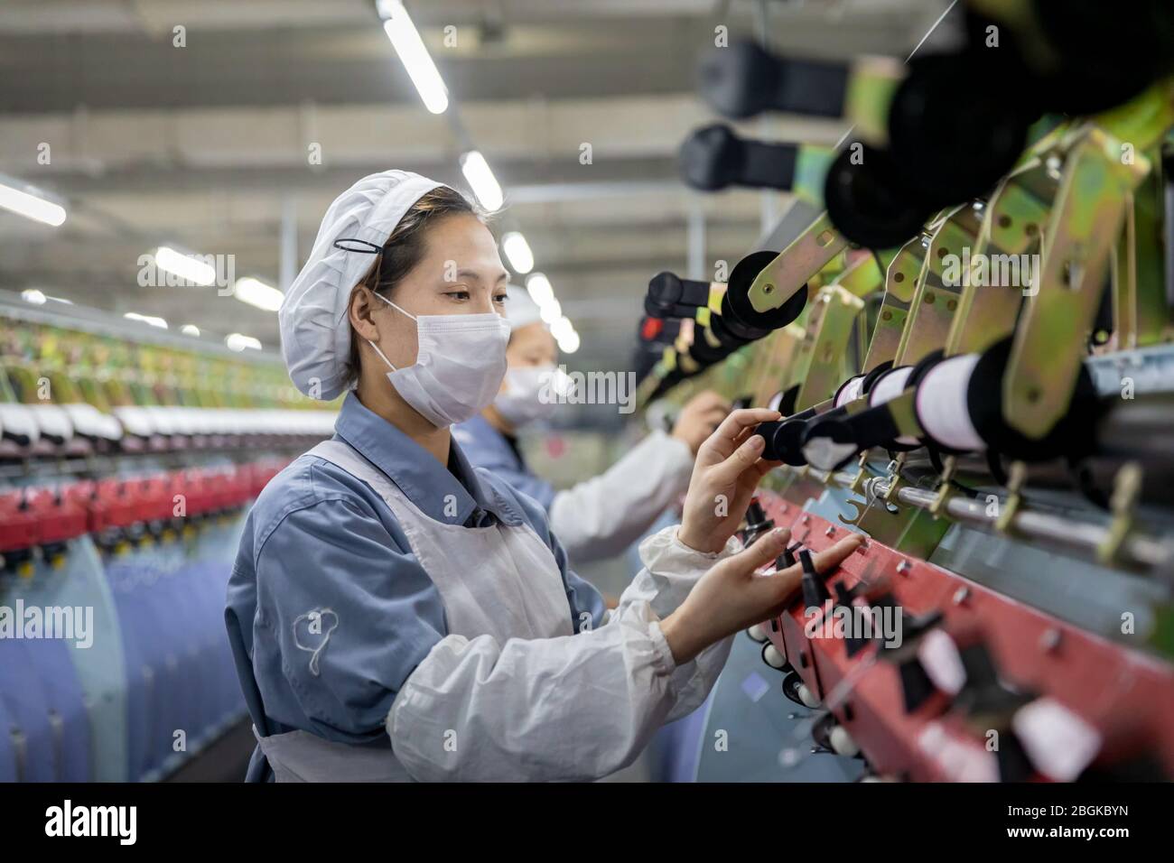 Staff at a local thread factory work along assembly line to produce to ...