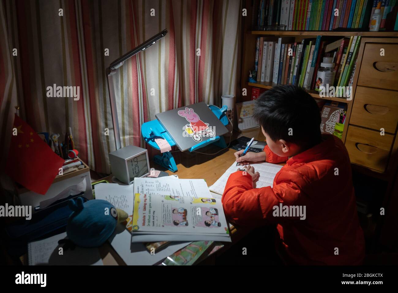 A primary school student does homework while taking classes via ...