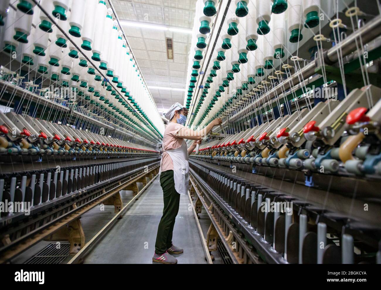 Staff at a local spinning mill work along automated production lines to ...