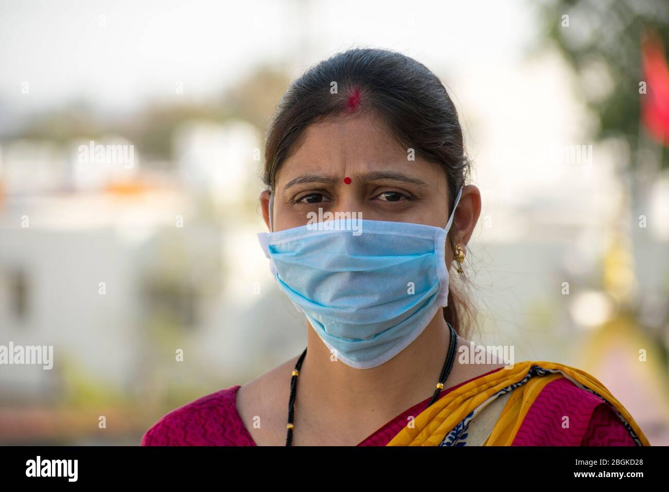 Detail of young indian woman wearing a white medical face mask. Focus ...
