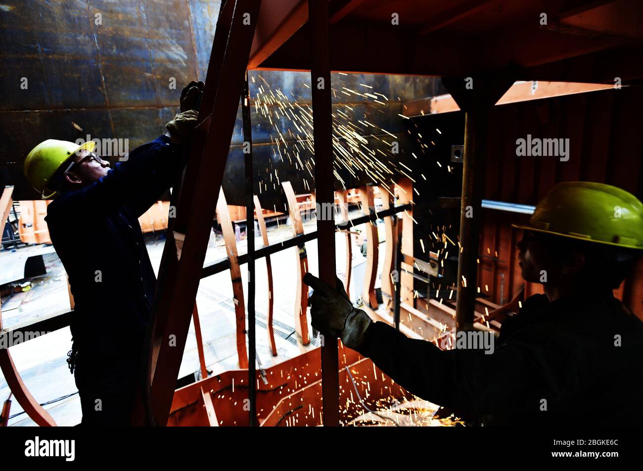 Staff work to produce a large vessel at a ship factory along the ...