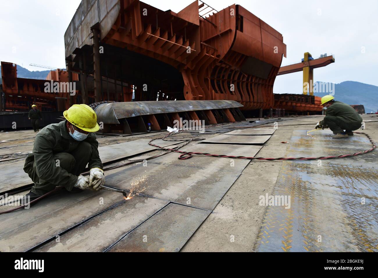 Staff work to produce a large vessel at a ship factory along the ...