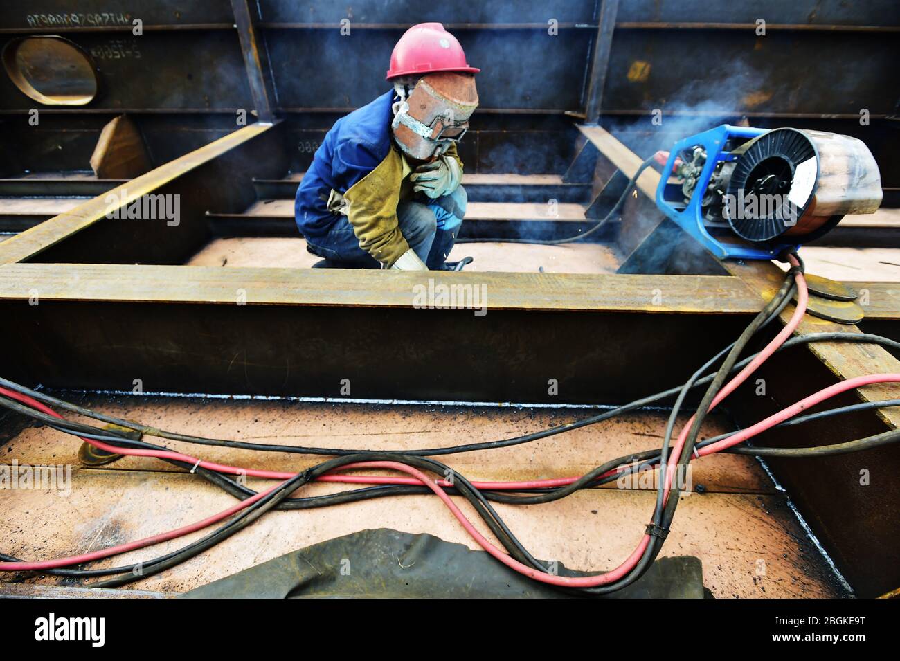 Staff work to produce a large vessel at a ship factory along the ...