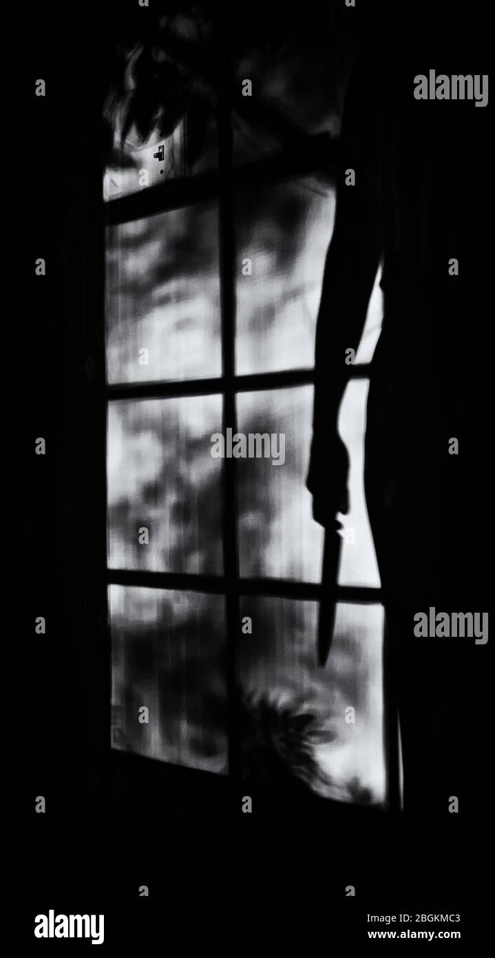 Silhouette of a person with a holding a large knife in hand, viewed ...