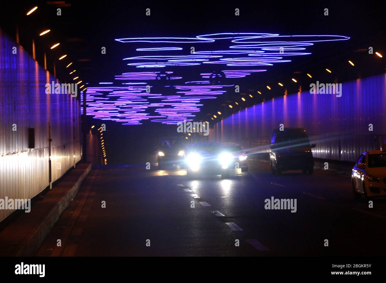 Vehicles move slowly in a 3000-meter-long tunnel, where blue LED light ...