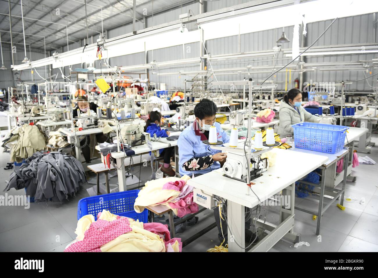 A factory worker sews clothes at a clothes factory in Qianxinan Miao ...