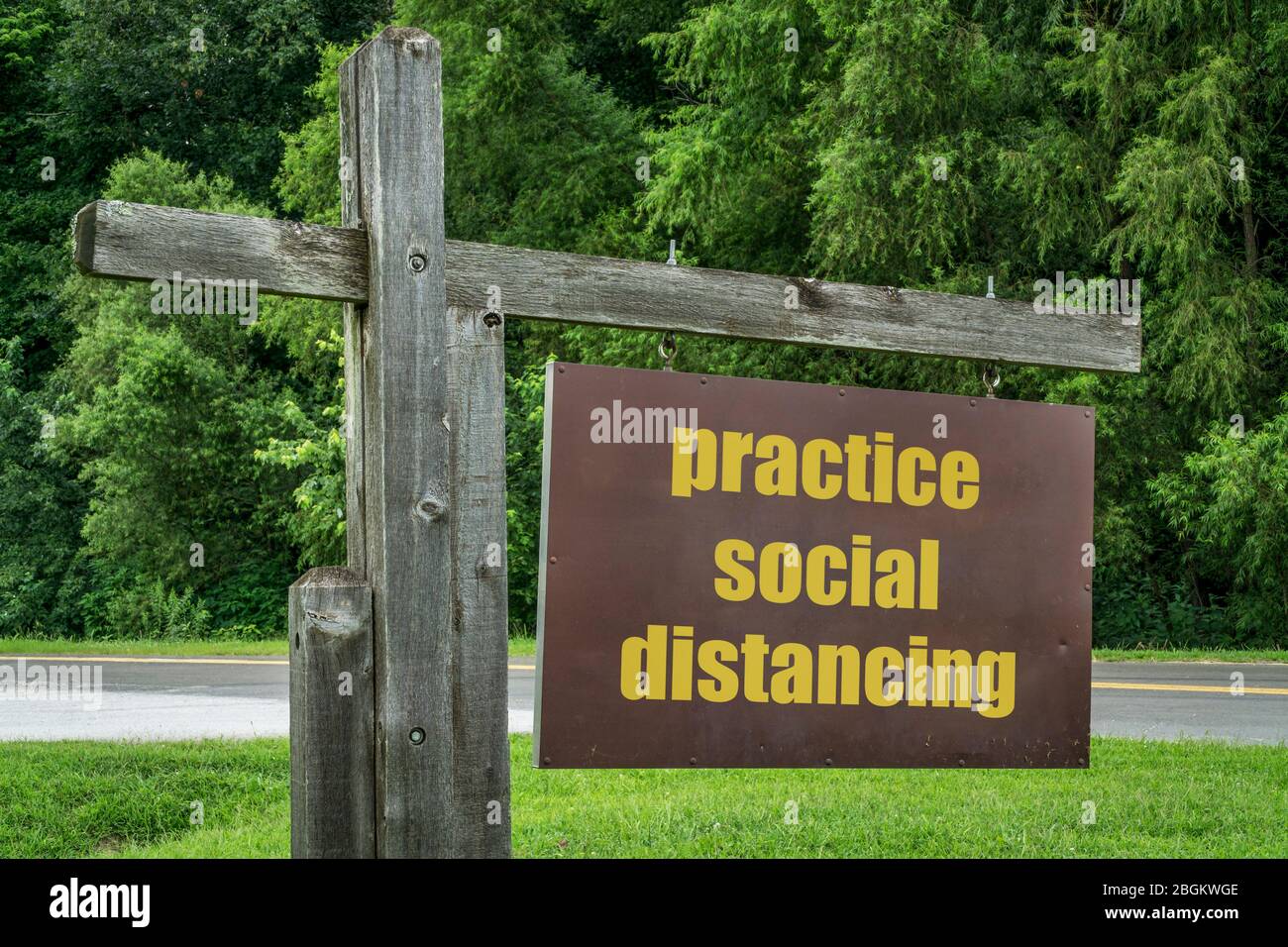 practice social distancing - park or trailhead sign against green trees ...