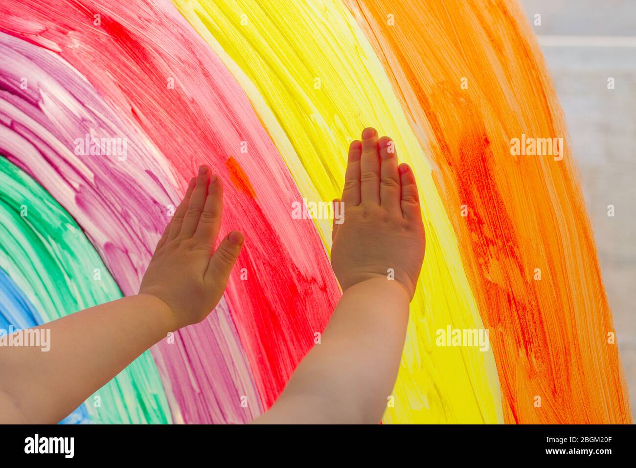 Child's hands touch painting rainbow on window Stock Photo - Alamy