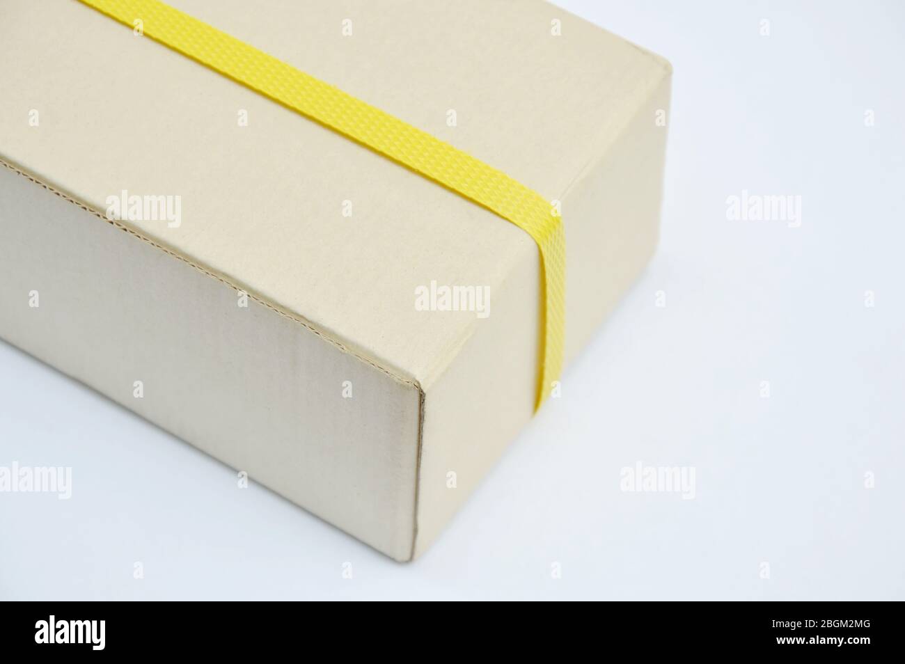 brown hard paper box wrapped by yellow plastic band on white background ...
