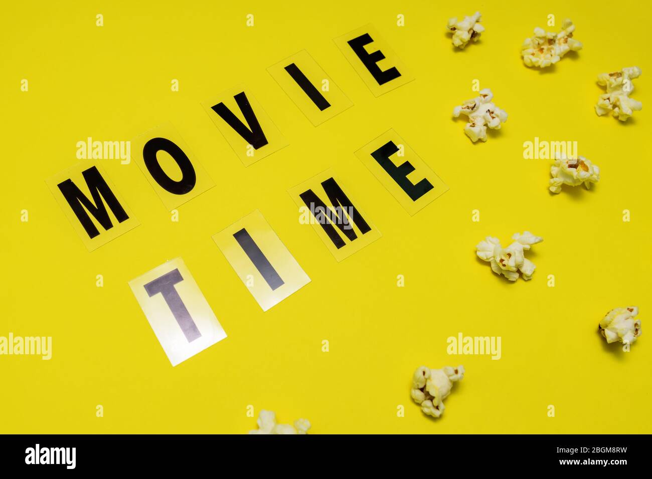 Movie Time text lettering with scattered salty popcorn on yellow ...