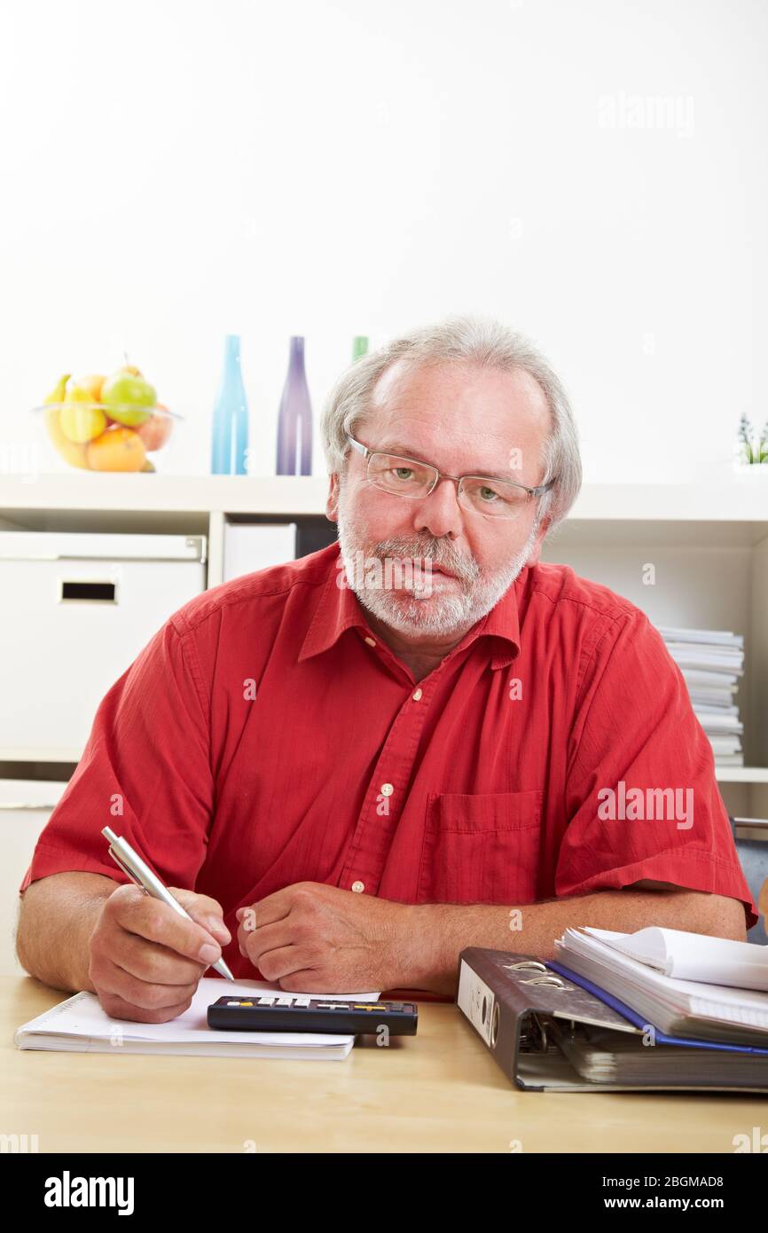 Senior calculates at desk with pen and calculator Stock Photo - Alamy