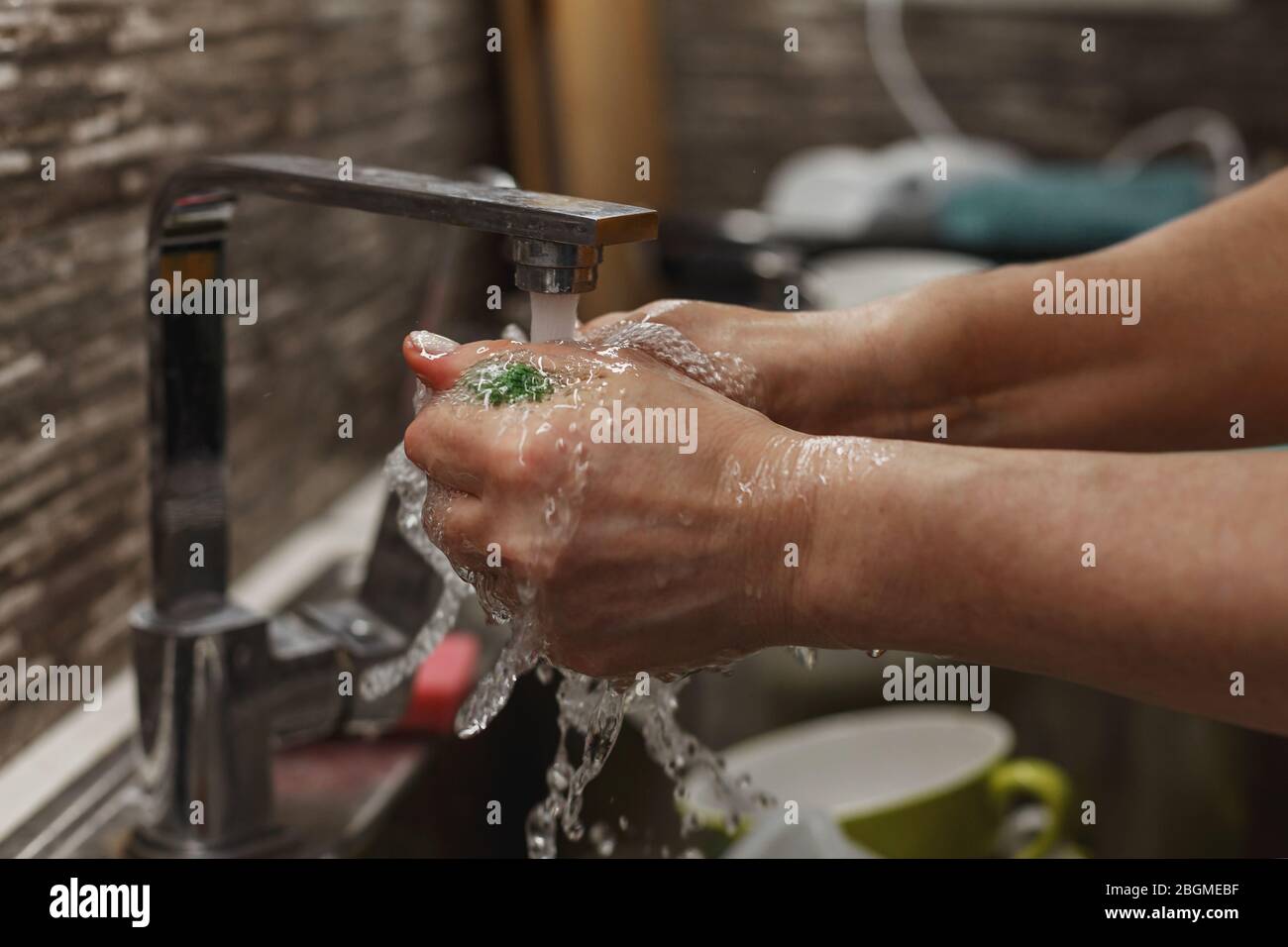 Process of washing cloth under running water above kitchen sink full of ...