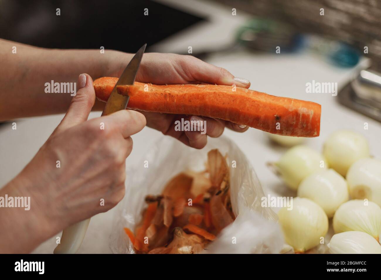 Woman's hands in process of peeling fresh carrot above small plastic ...