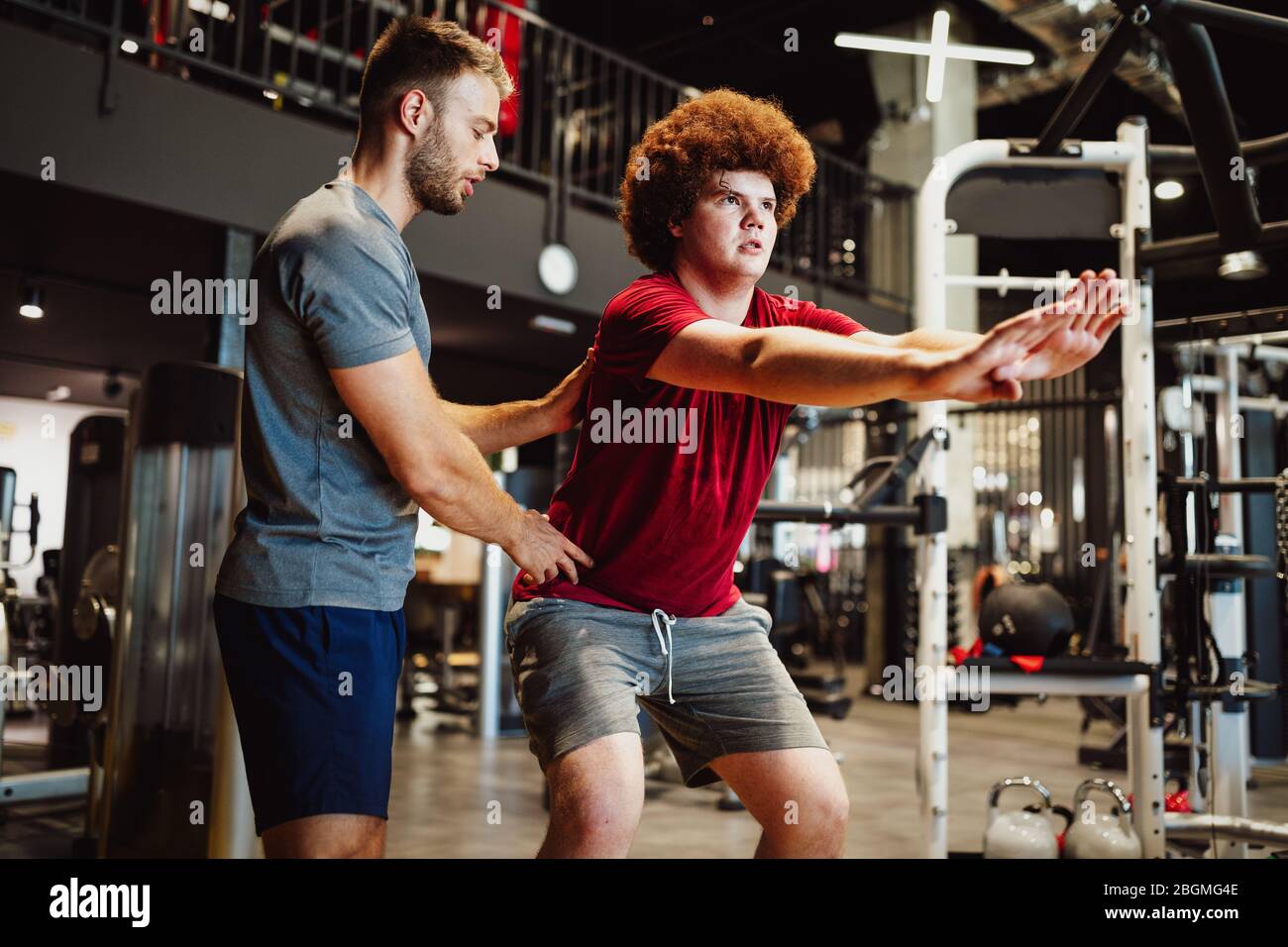 Overweight young man exercising gym with personal trainer Stock Photo ...