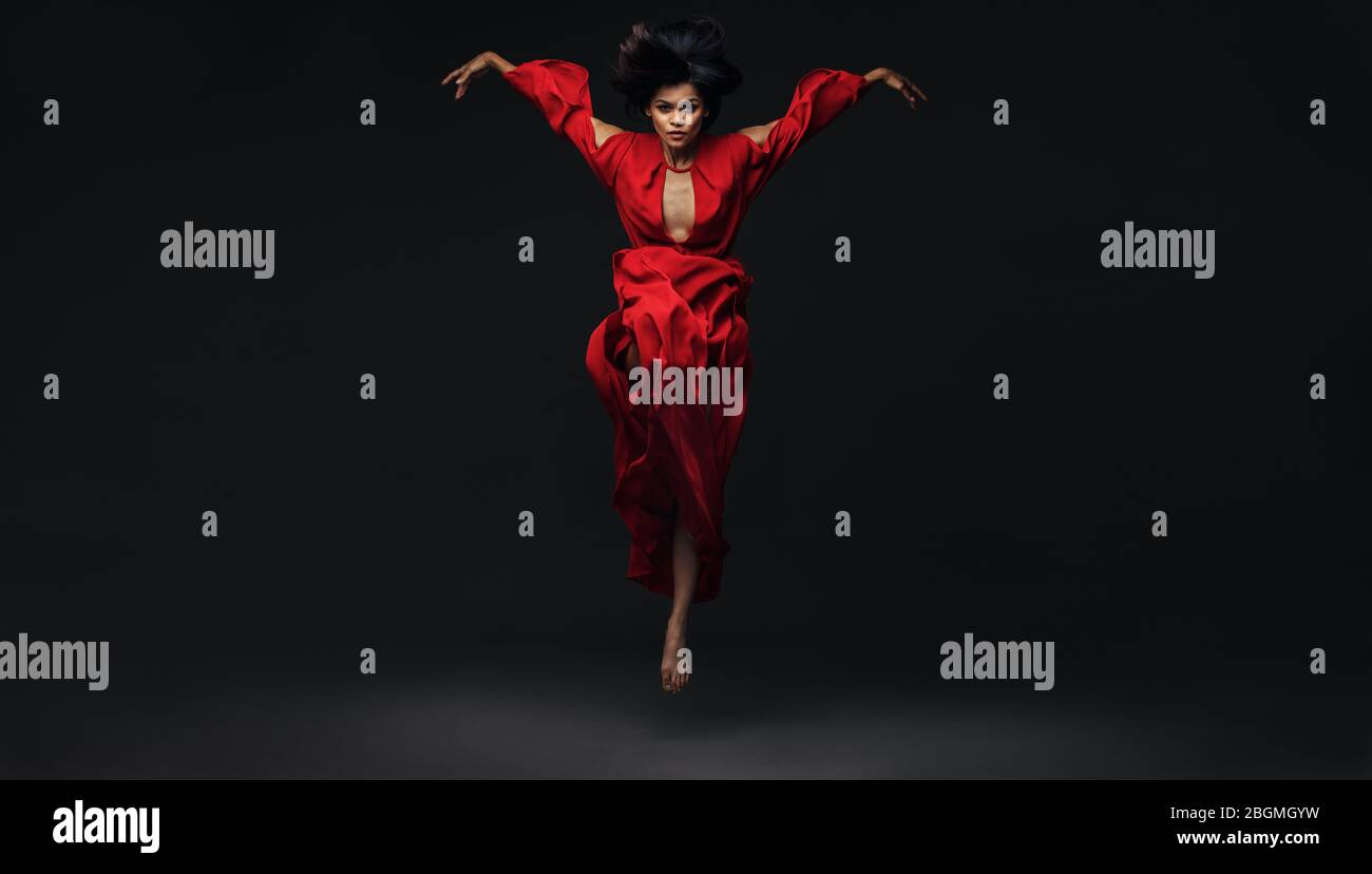Beautiful woman in red dress dancing in studio. Female dancer ...